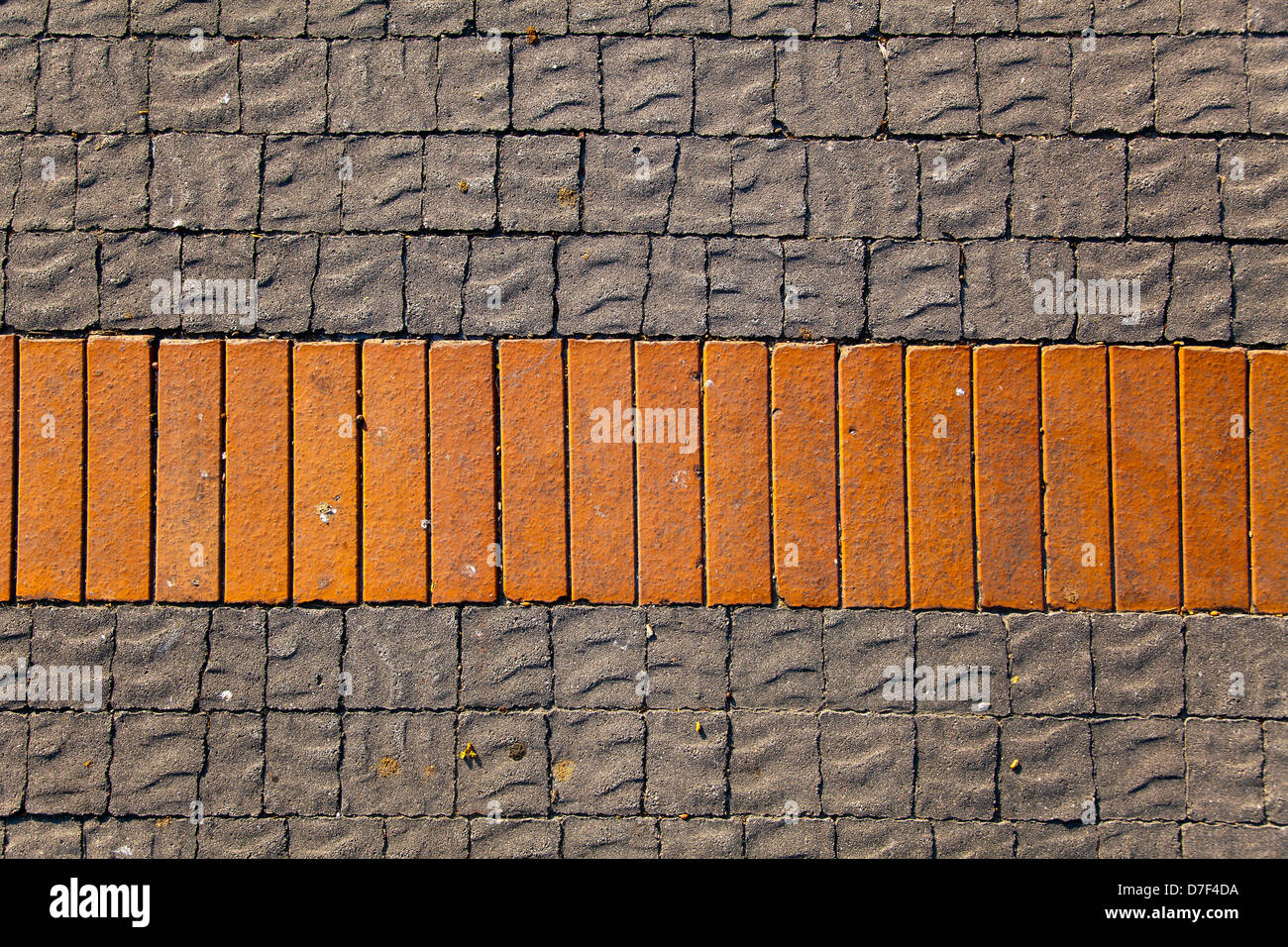 Gray floor tiles with wavy/rippled texture and red bricks lit by direct ...
