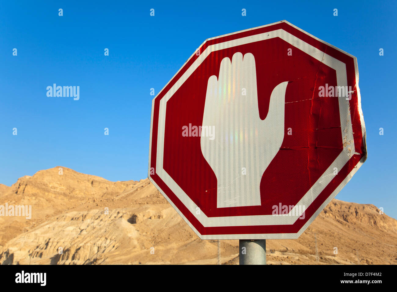A damaged stop sign on the background of a desert mountain and clear ...