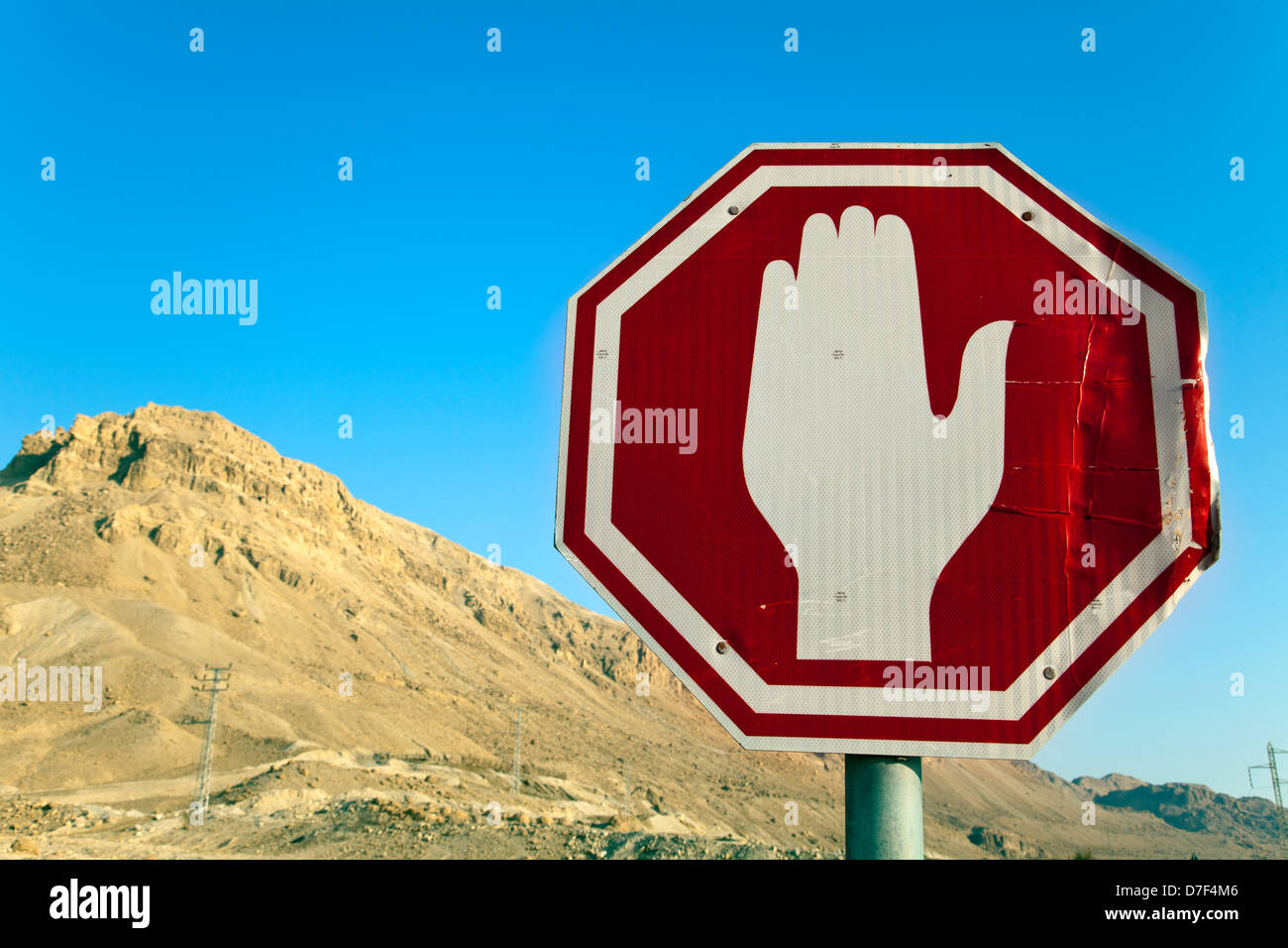 A damaged stop sign on the background of a desert mountain and clear ...