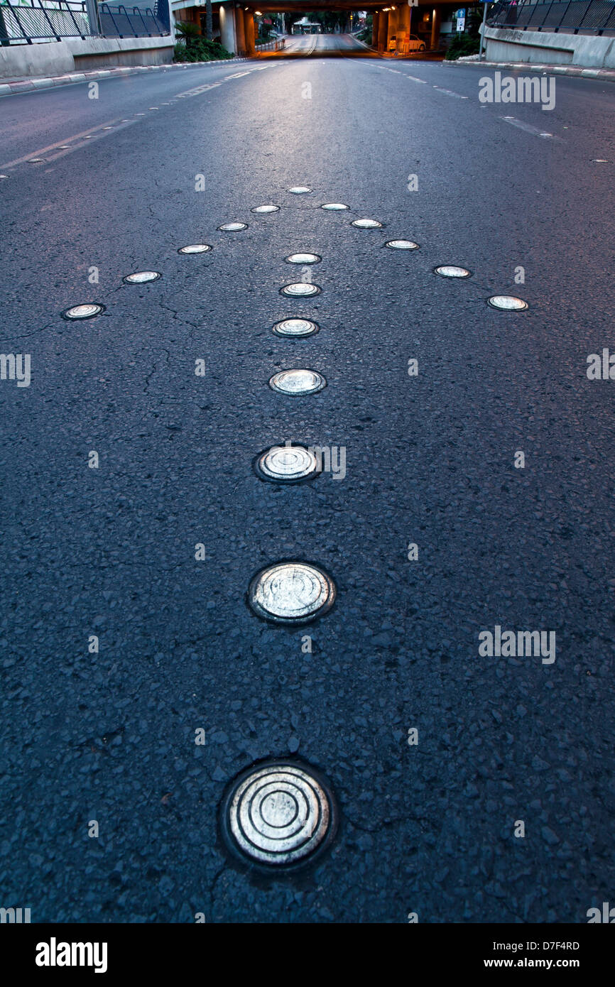 Metallic directional arrow pointing forward on an empty street in Tel ...