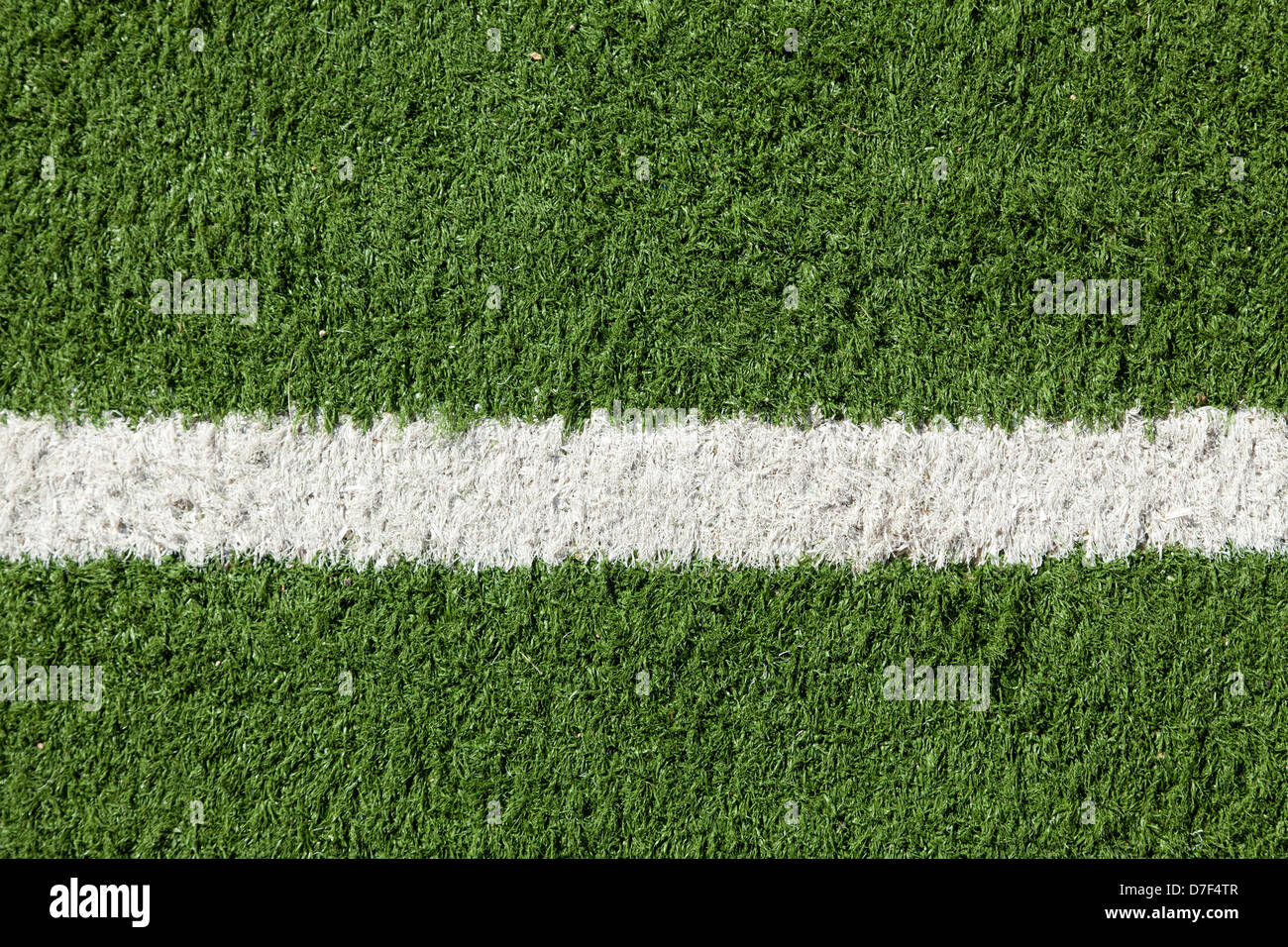 Close up of artificaial lawn with a white stripe painted on it. Part of ...
