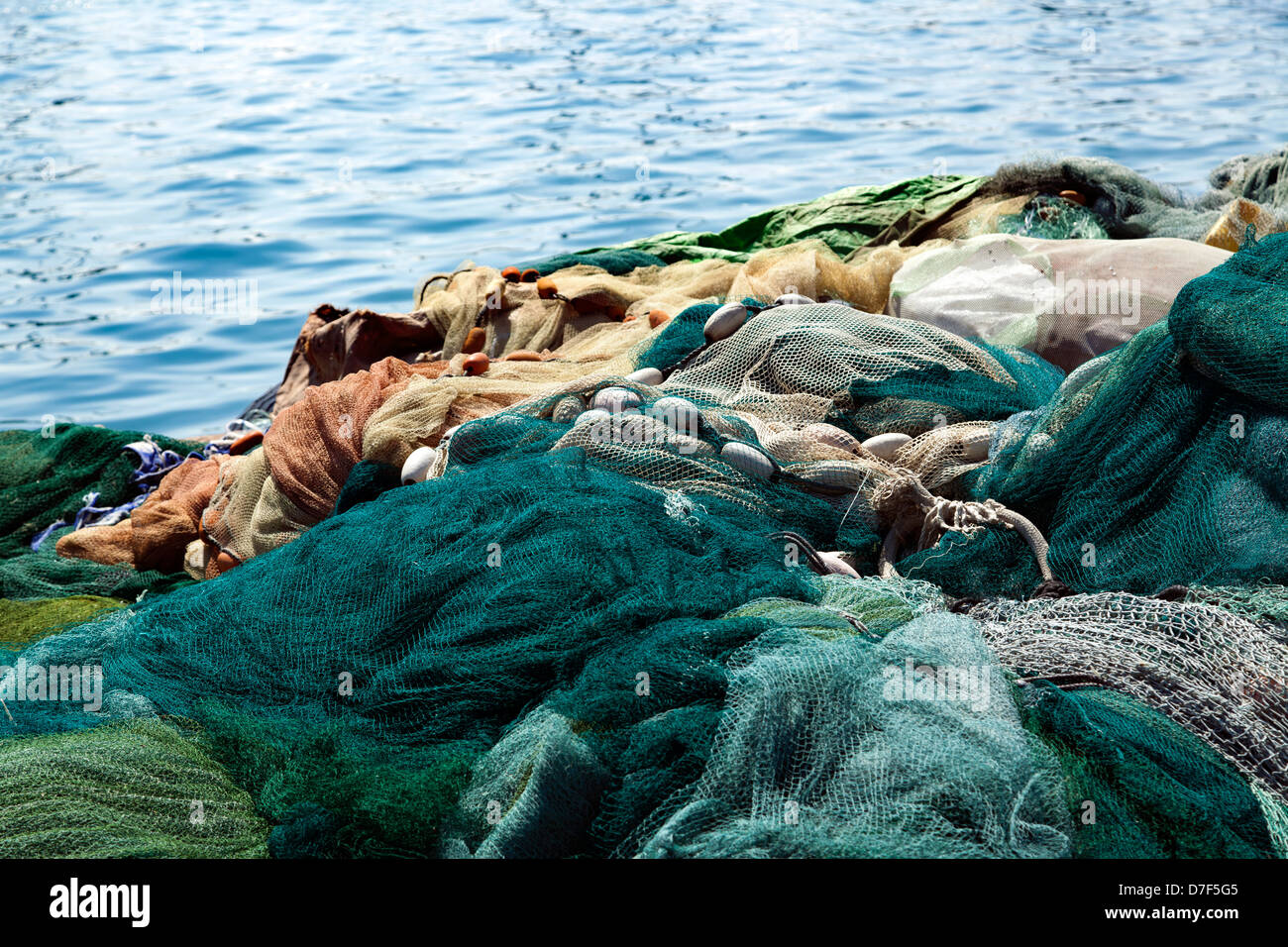 A large pile fishnets out duty resting on commercial dock in sunlight ...