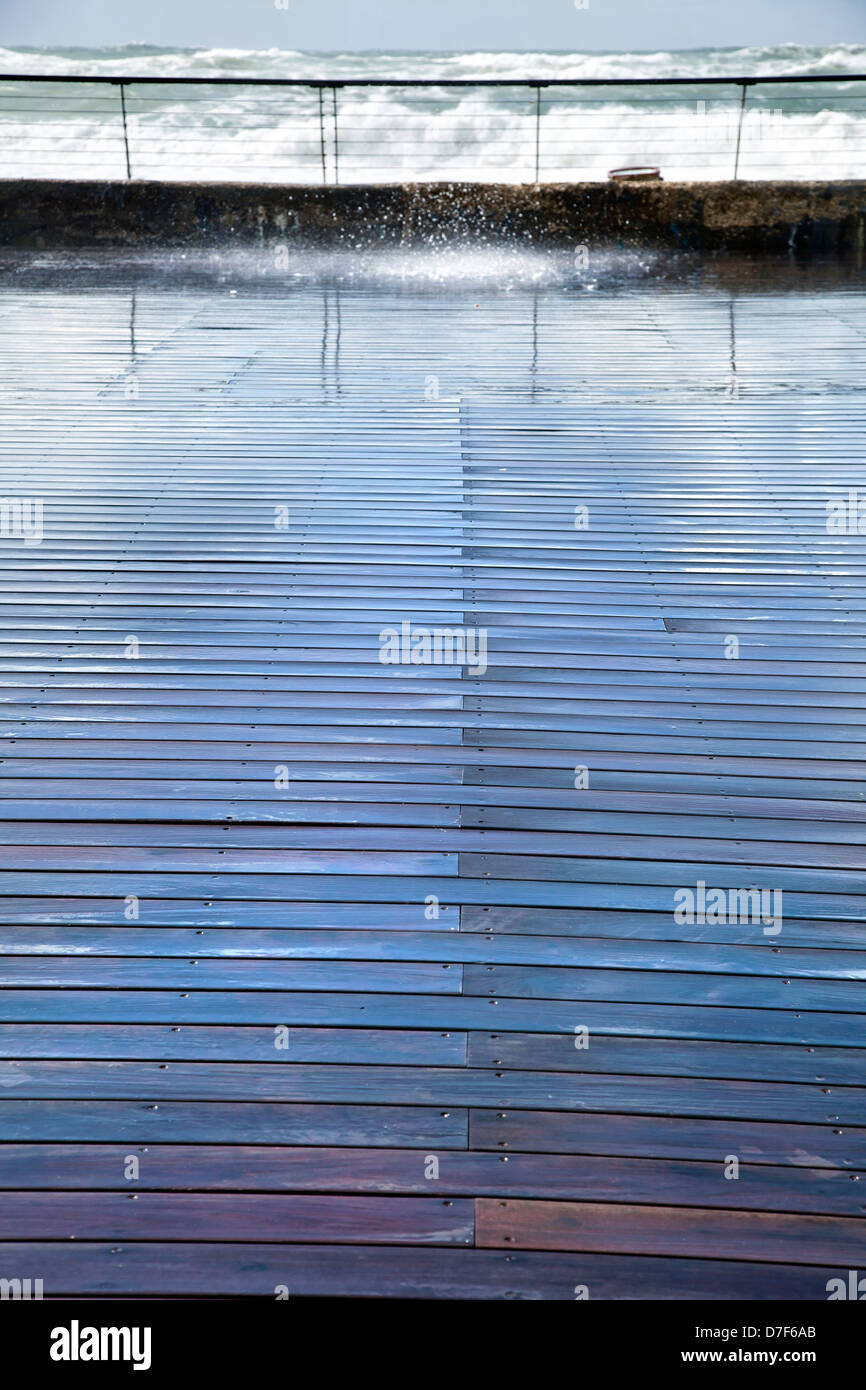 Wooden deck floor of a boardwalk, water sprayed by ricochets splashed ...