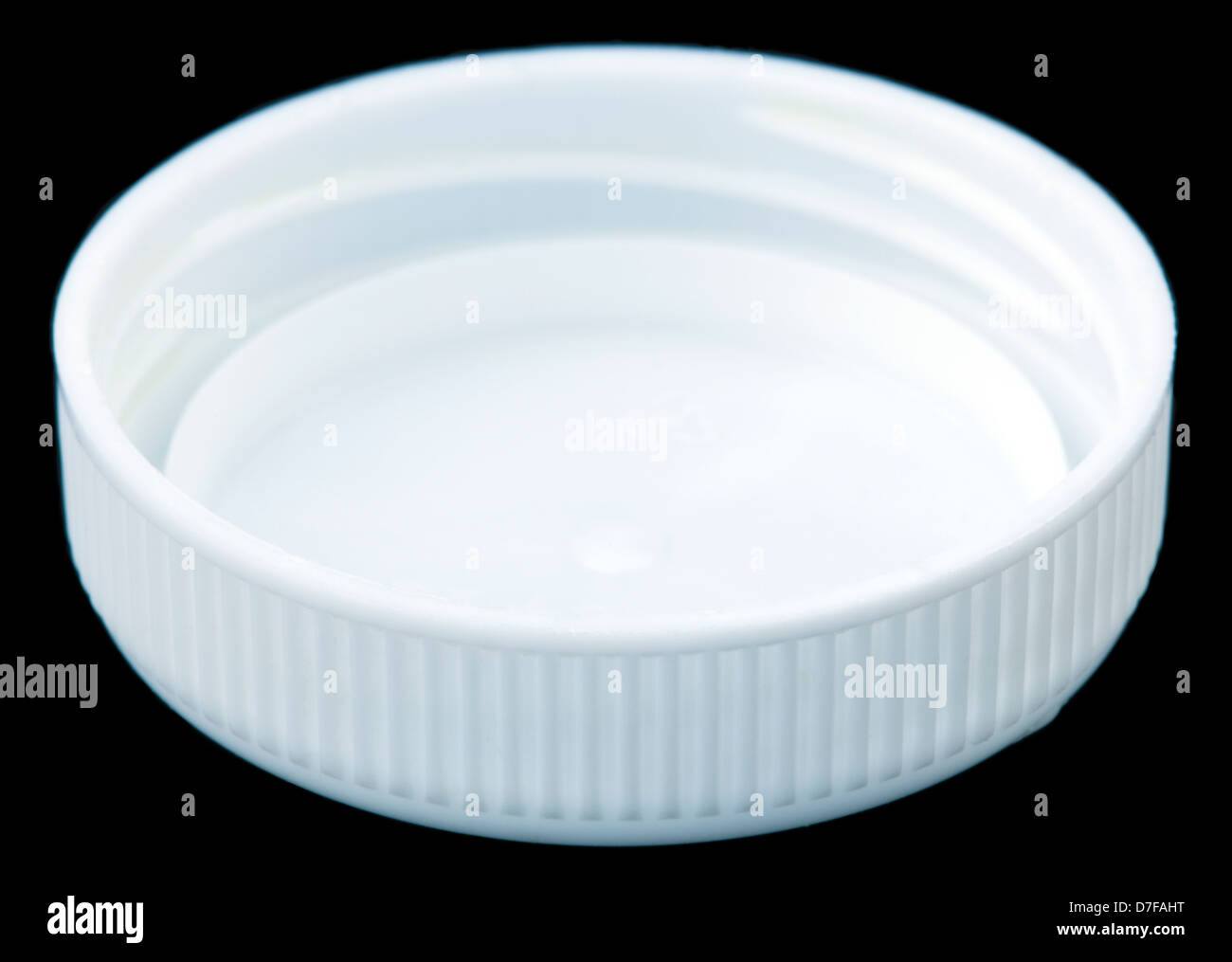 The bottom side of a white plastic bottle cap seen from a slightly high ...