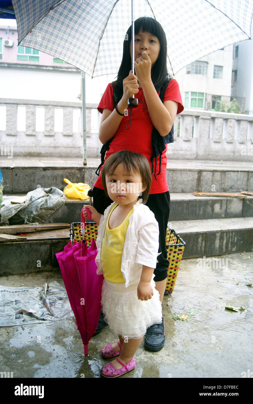 Cute little Chinese girl in the market, rainy day. In Shenzhen, China ...