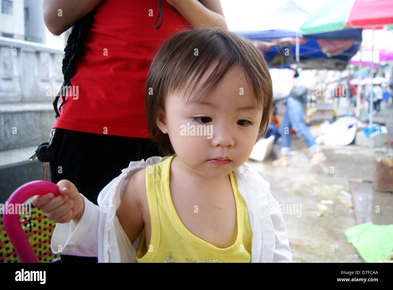 Cute little Chinese girl in the market, rainy day. In Shenzhen, China ...