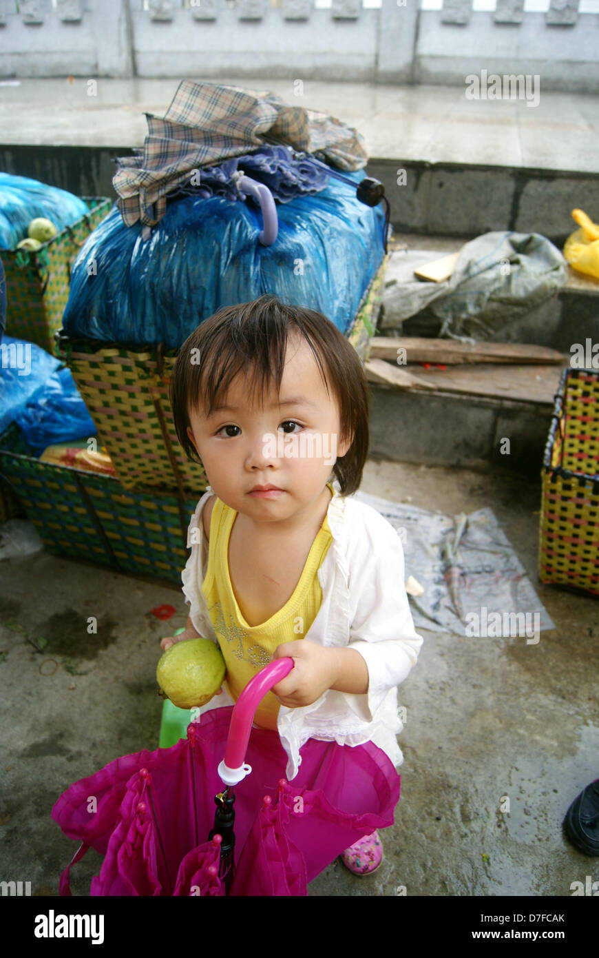 Cute little Chinese girl in the market, rainy day. In Shenzhen, China ...
