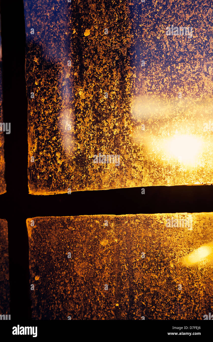 Afternoon yellow sun is back-lighting a window stained with drop marks ...