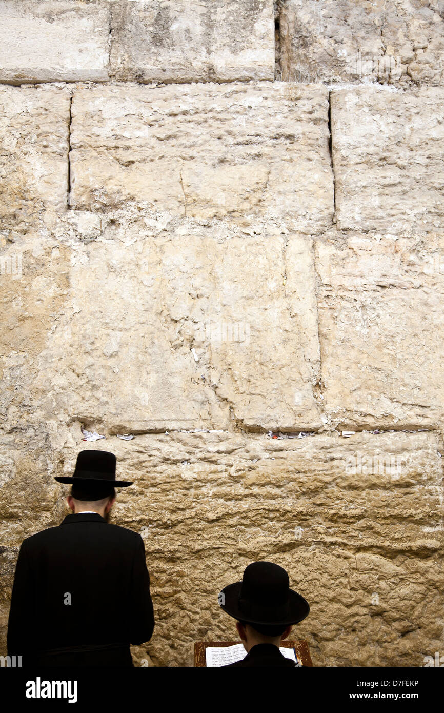 Two Jewish orthodox men, one standing and one sitting, praying at the ...