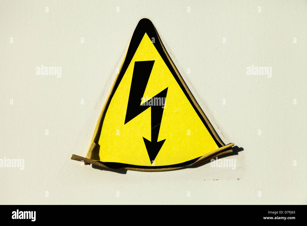 Old electric hazard sticker starting to peel off of the bright beige ...