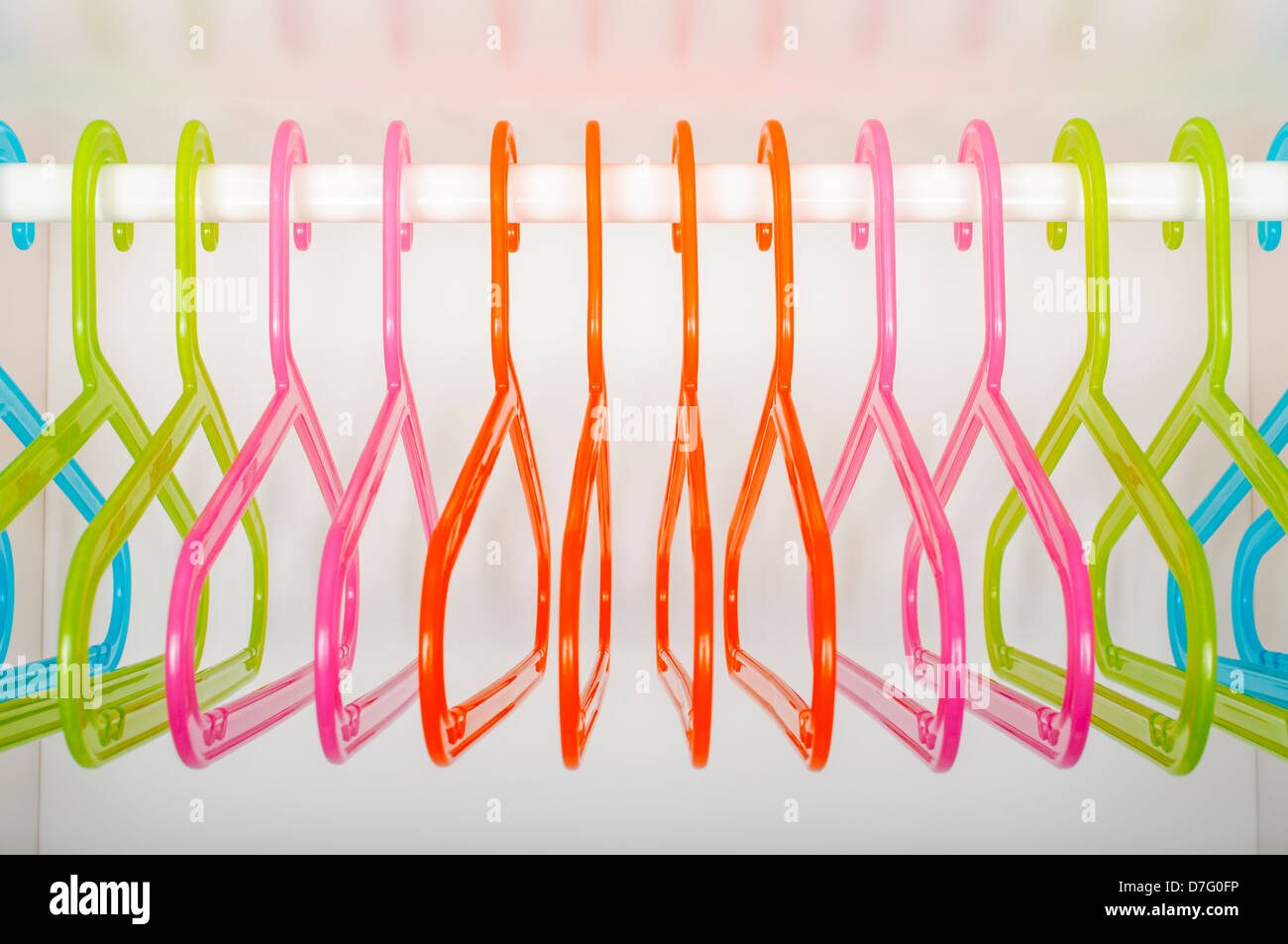 Colored plastic hangers hanging on a rod in an empty white closet Stock ...