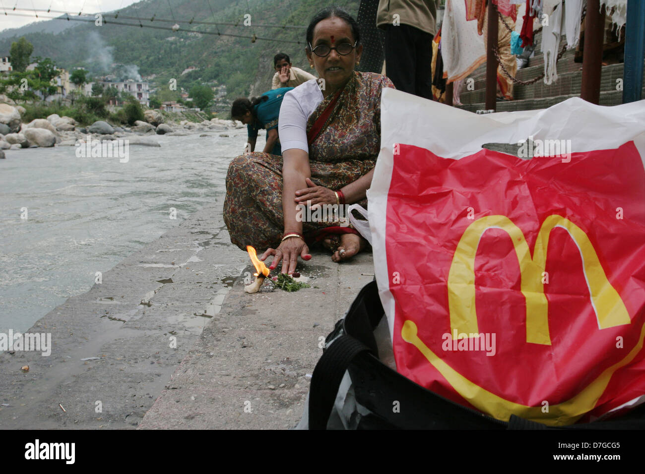 A pilgrim performs her puja (prayer ceremony) on the banks of the ...