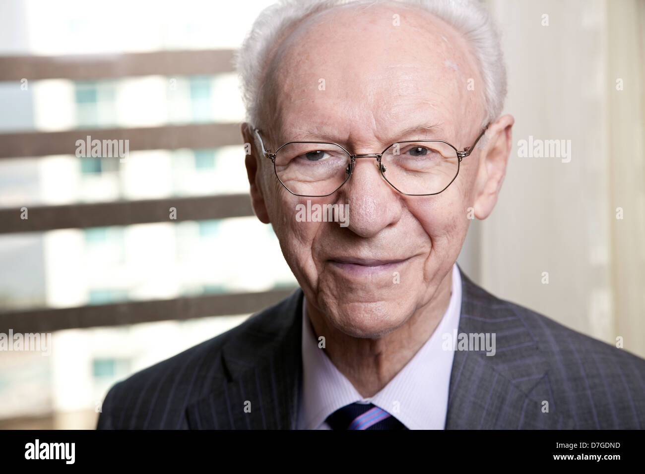 Close-up portrait senior businessman (in his 80's) smiling to camera ...