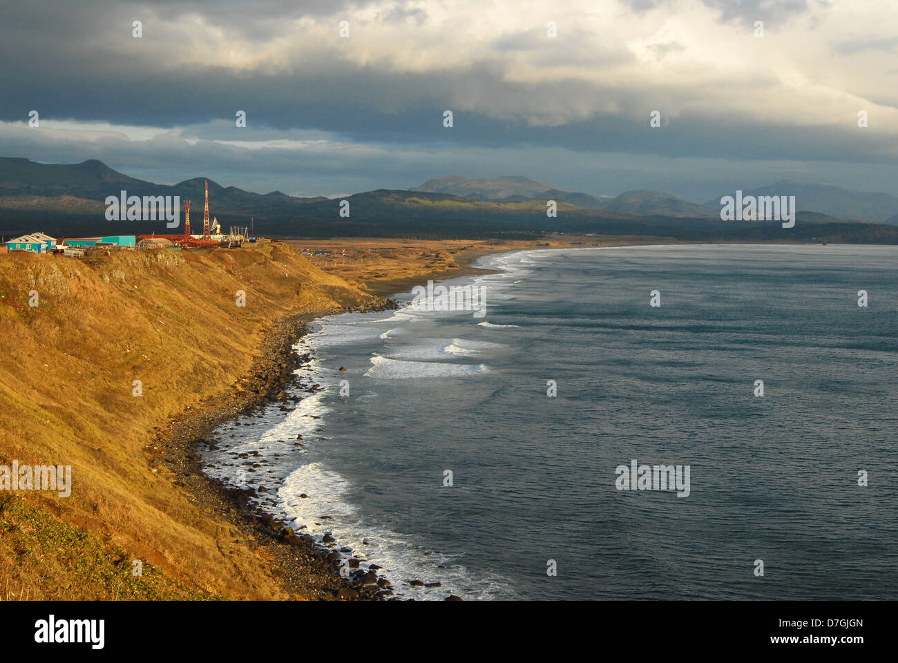 Few houses in the outskirts of South Kurilsk town at the high coast of ...