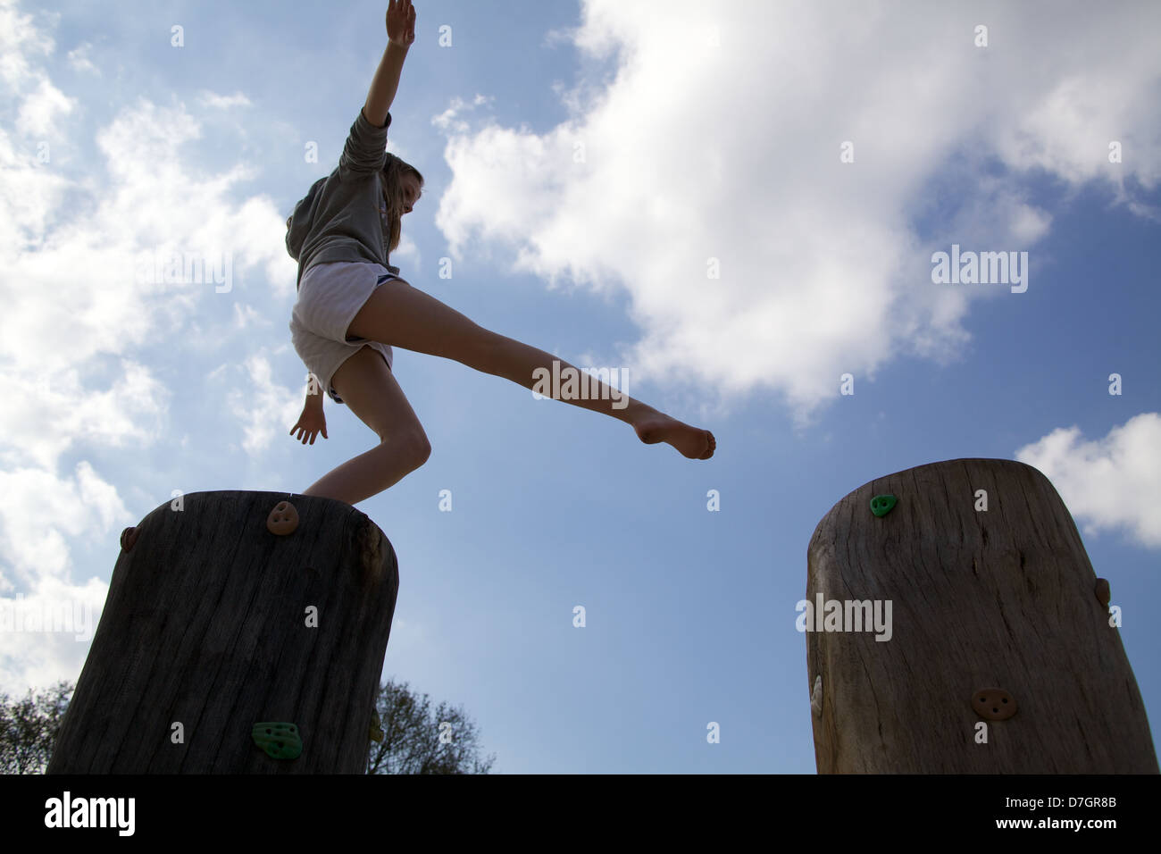 girl balancing on tree trunk attempting to take a wide step Stock Photo ...