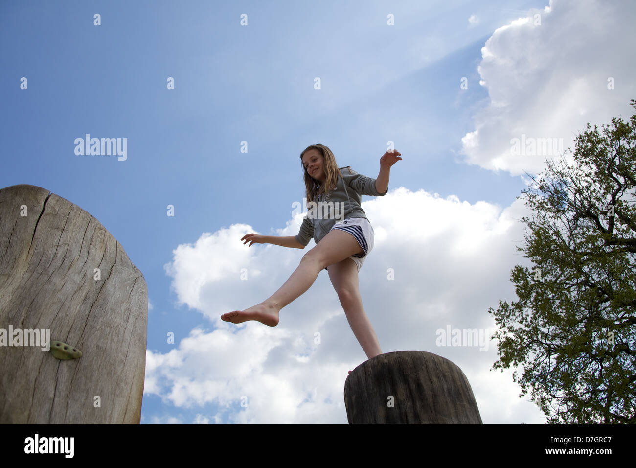 girl balancing on tree trunk attempting to take a wide step Stock Photo ...