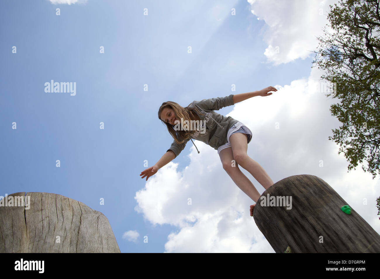 girl balancing on tree trunk attempting to take a wide step Stock Photo ...