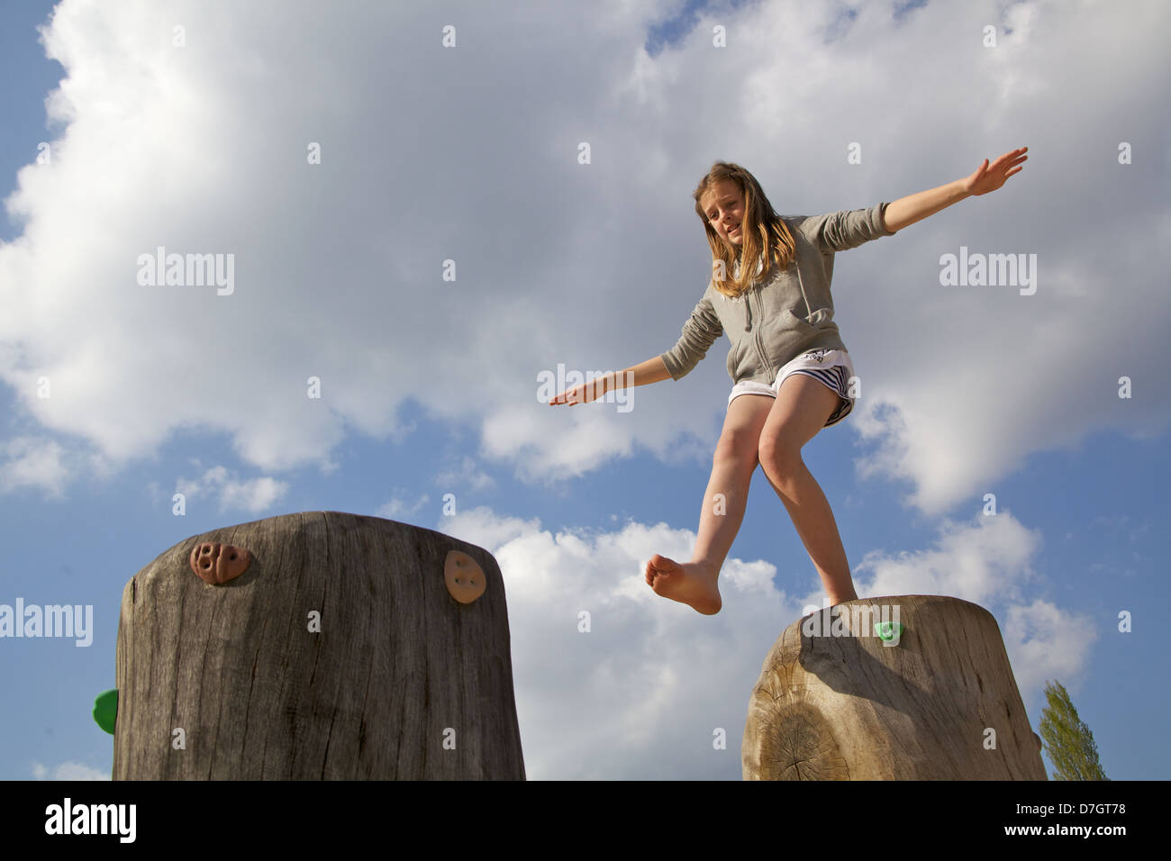 girl balancing on tree trunk attempting to take a wide step Stock Photo ...