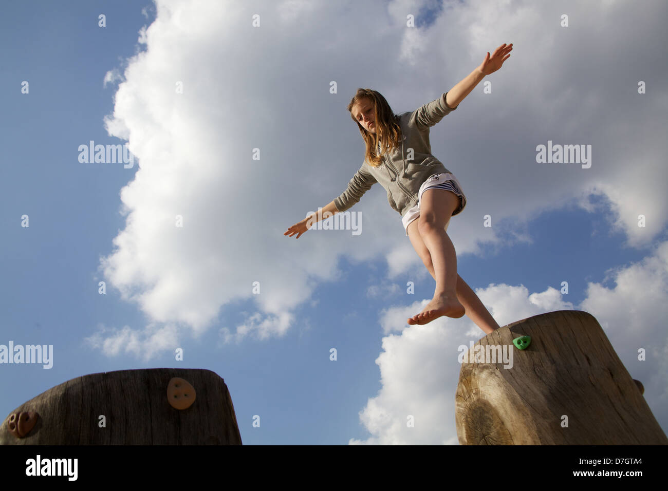 girl balancing on tree trunk attempting to take a wide step Stock Photo ...