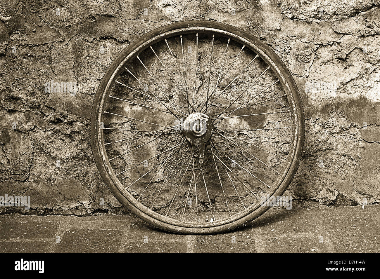 antique bicycle wheel isolated against old wall background Stock Photo ...