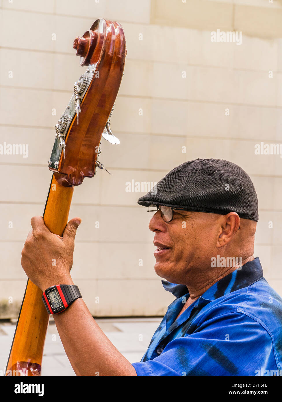 A male Cuban street musician plays his bass and sings as he looks to ...