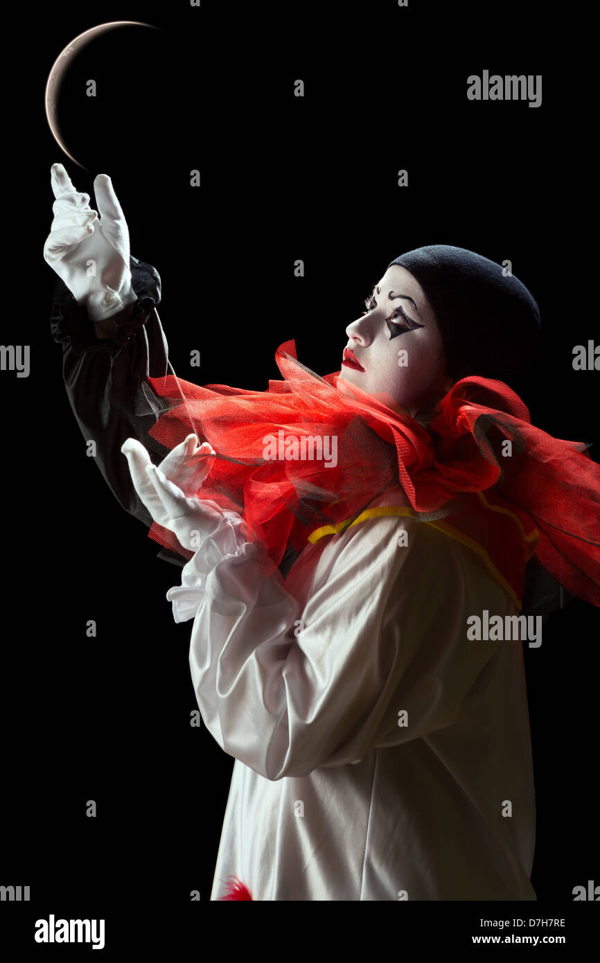 Beautiful Pierrot clown playing mime with the moon Stock Photo - Alamy