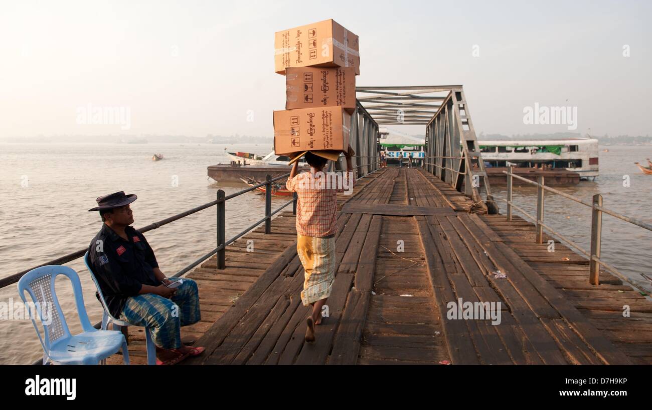 A woman carries several cardboard boxes on her head over a bridge at ...