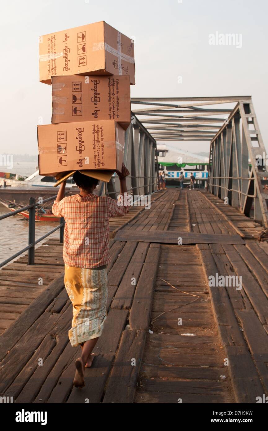 A woman carries several cardboard boxes on her head over a bridge at ...