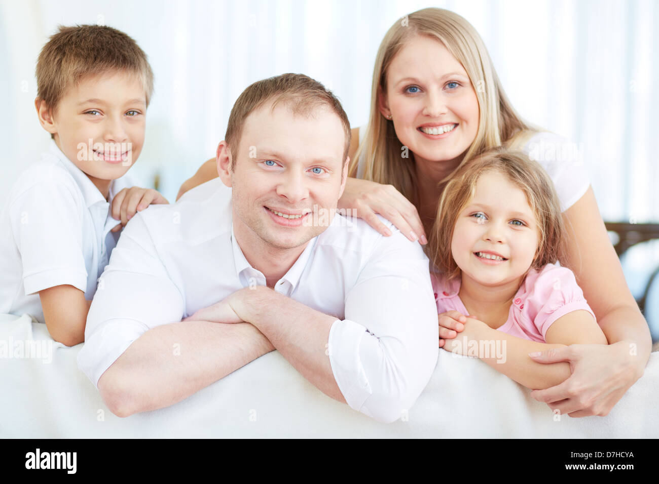 Portrait of happy parents with two children looking at camera at home ...