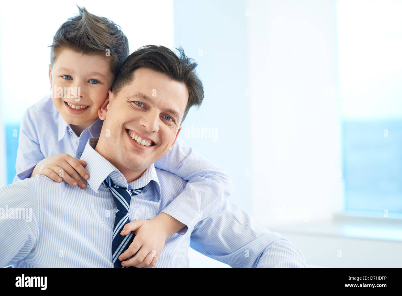 Photo of happy boy embracing his dad and both looking at camera Stock ...
