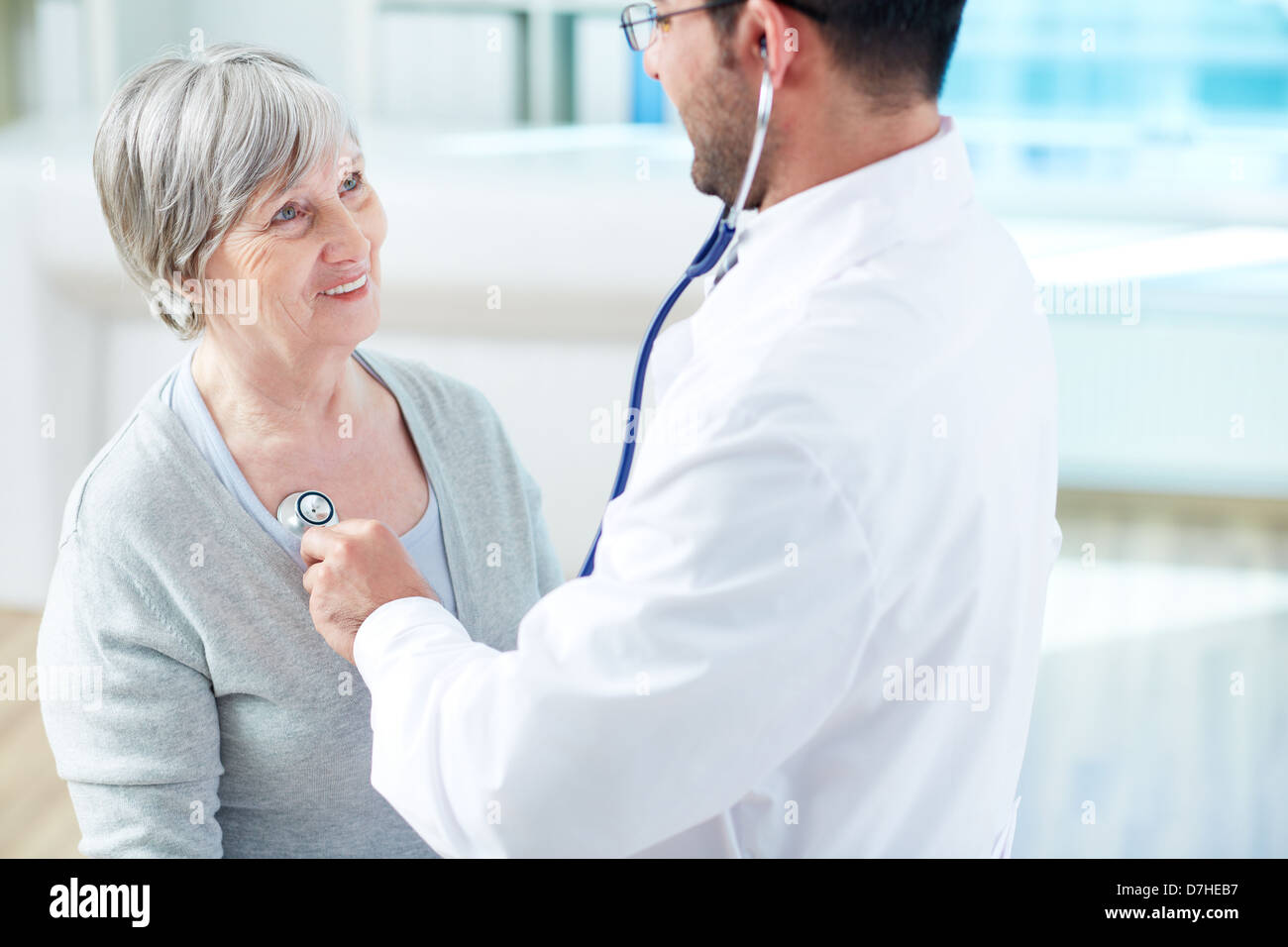 Confident doctor examining his senior patient in hospital Stock Photo ...