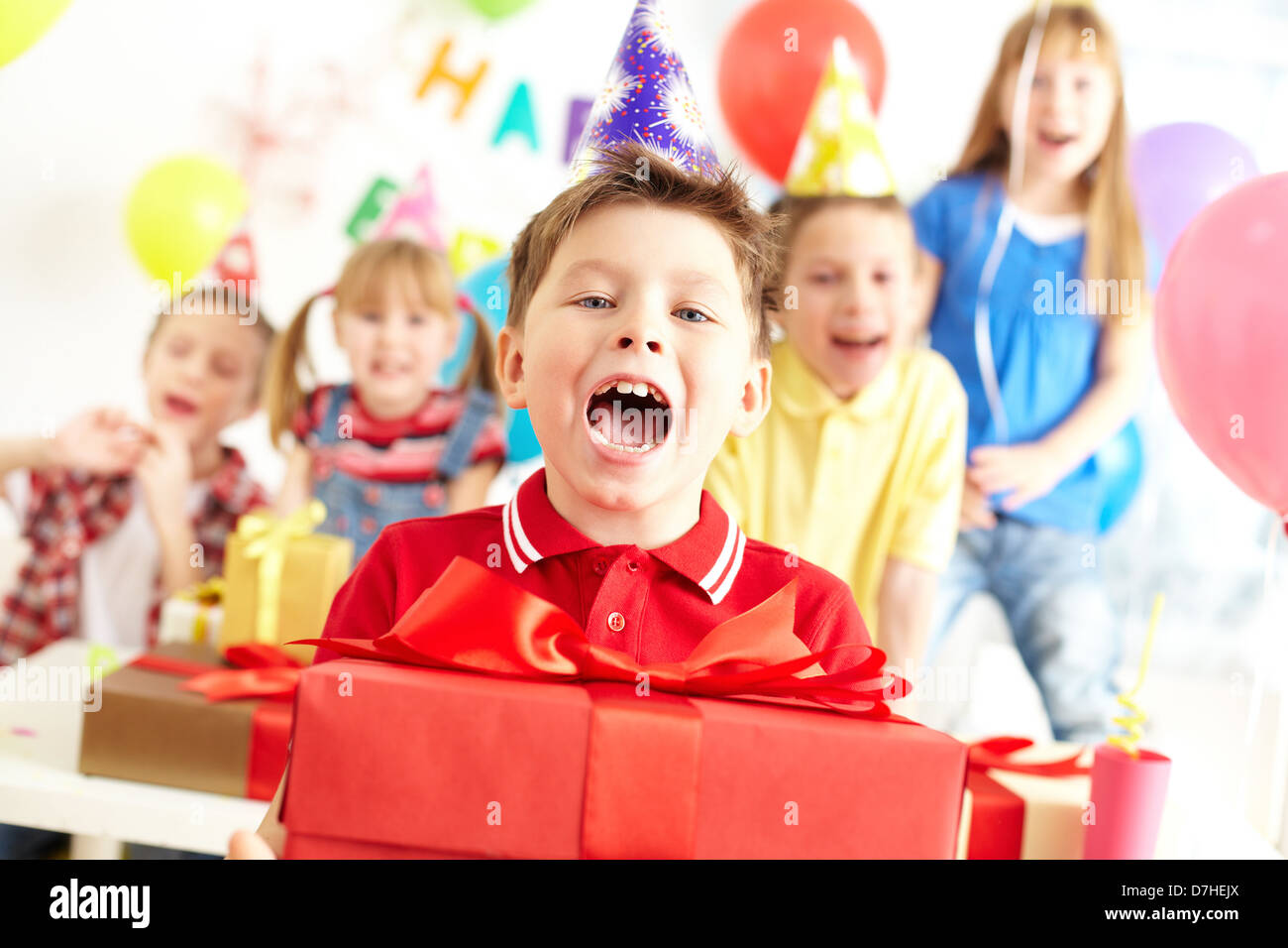 Joyful boy with present looking at camera with his friends on ...