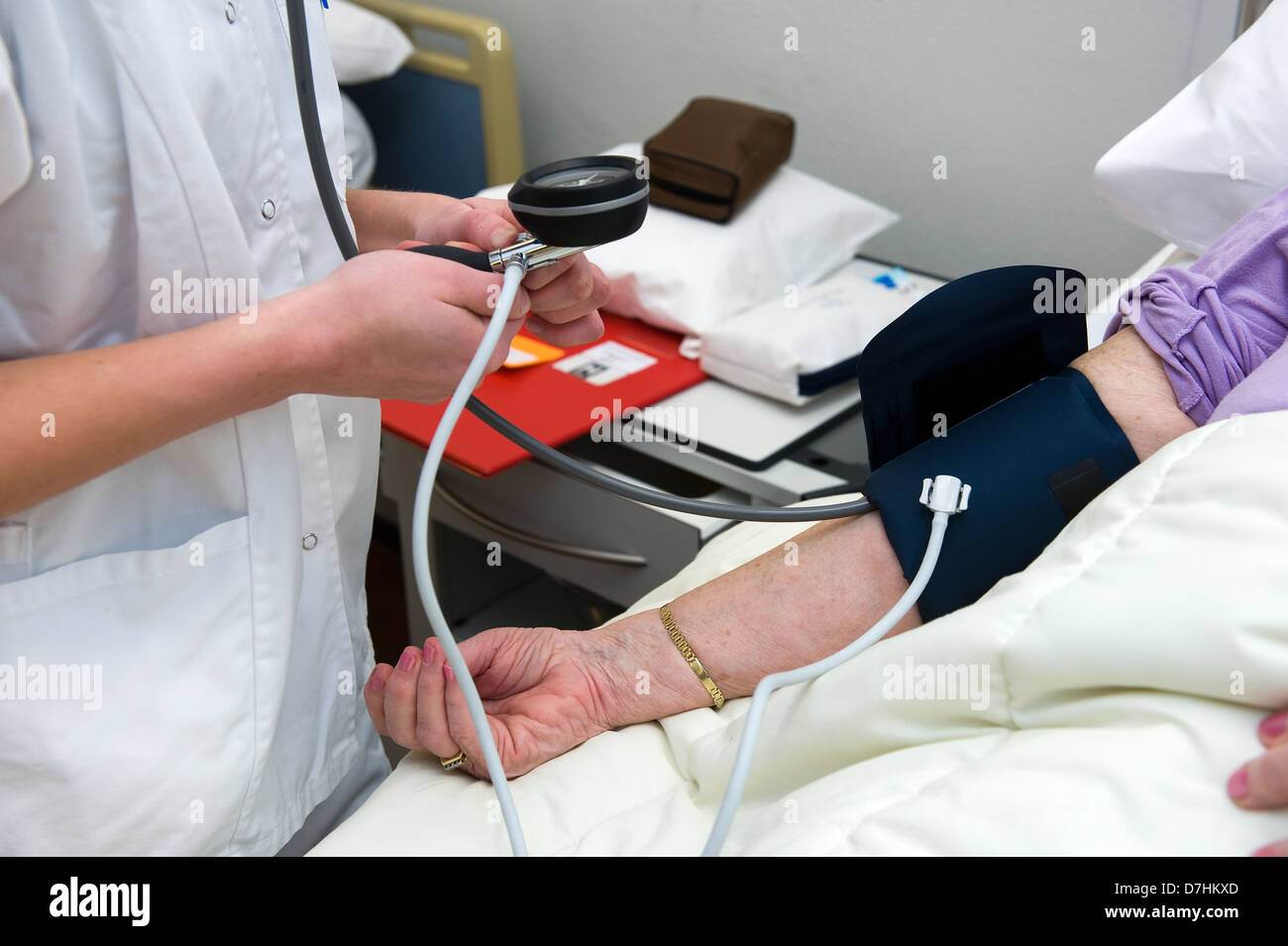 A nurse is measuring the blood pressure from a patient in a hospital ...