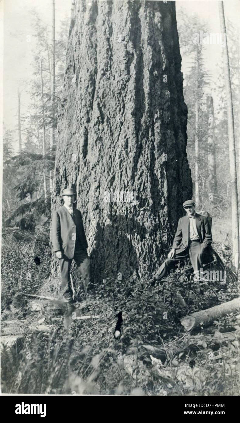 The photograph depicts two men dressed in suits standing next to a ...