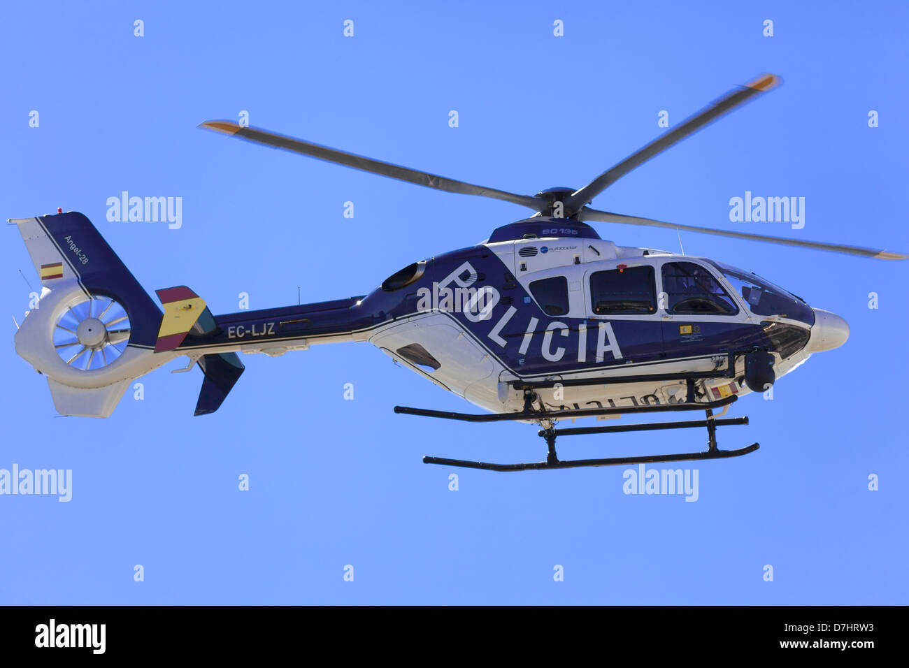 Spanish Police twin engine Eurocopter EC135 flying against a blue sky ...
