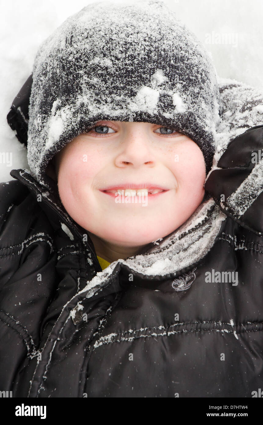 An 8 year old boy plays in the snow. His hat is caked with snow Stock ...