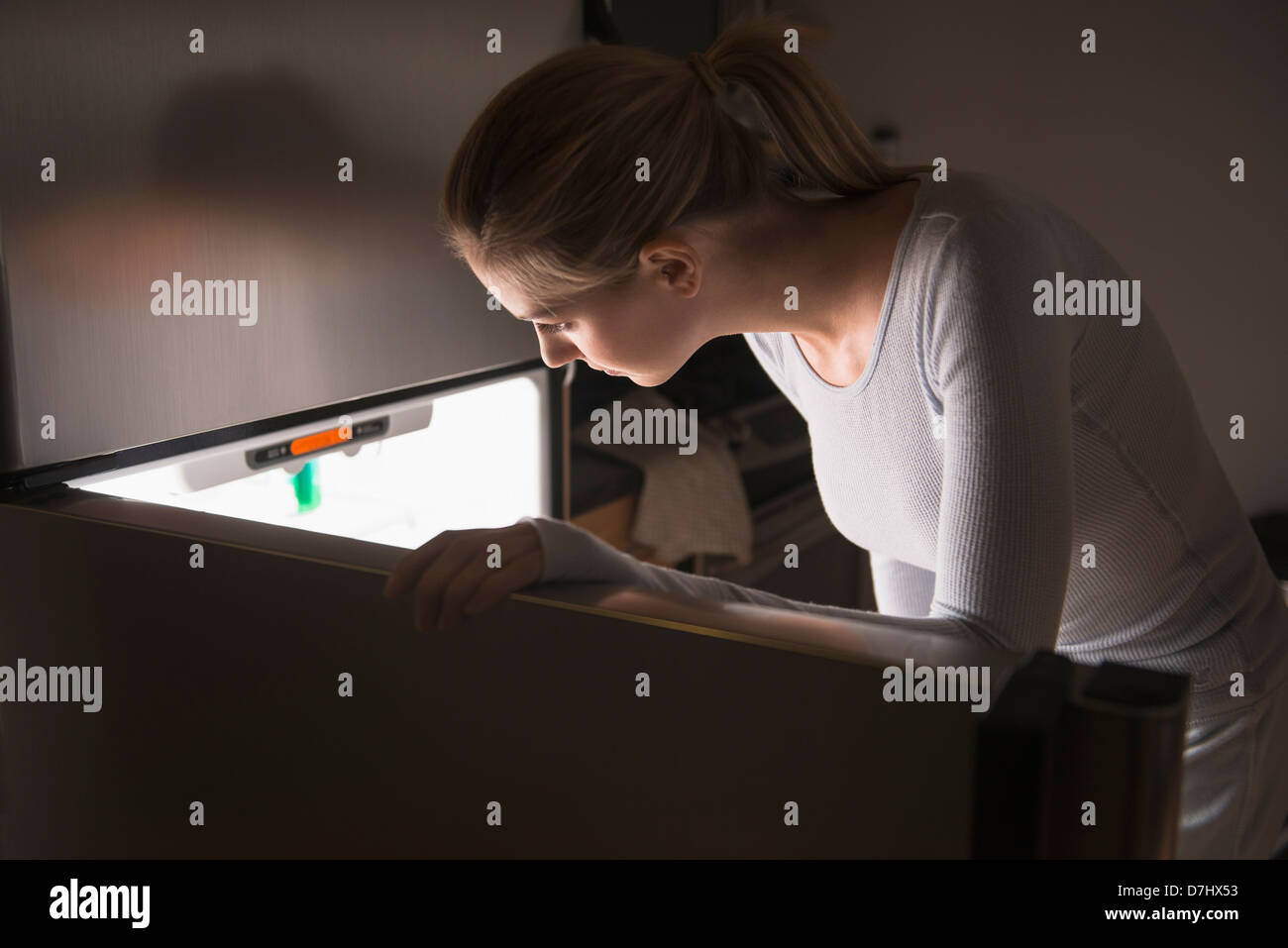 Woman opening fridge at night Stock Photo - Alamy