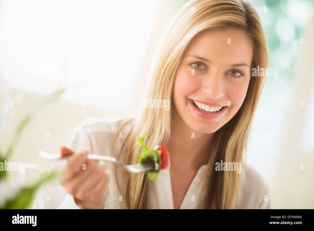 Portrait of woman eating and smiling Stock Photo - Alamy