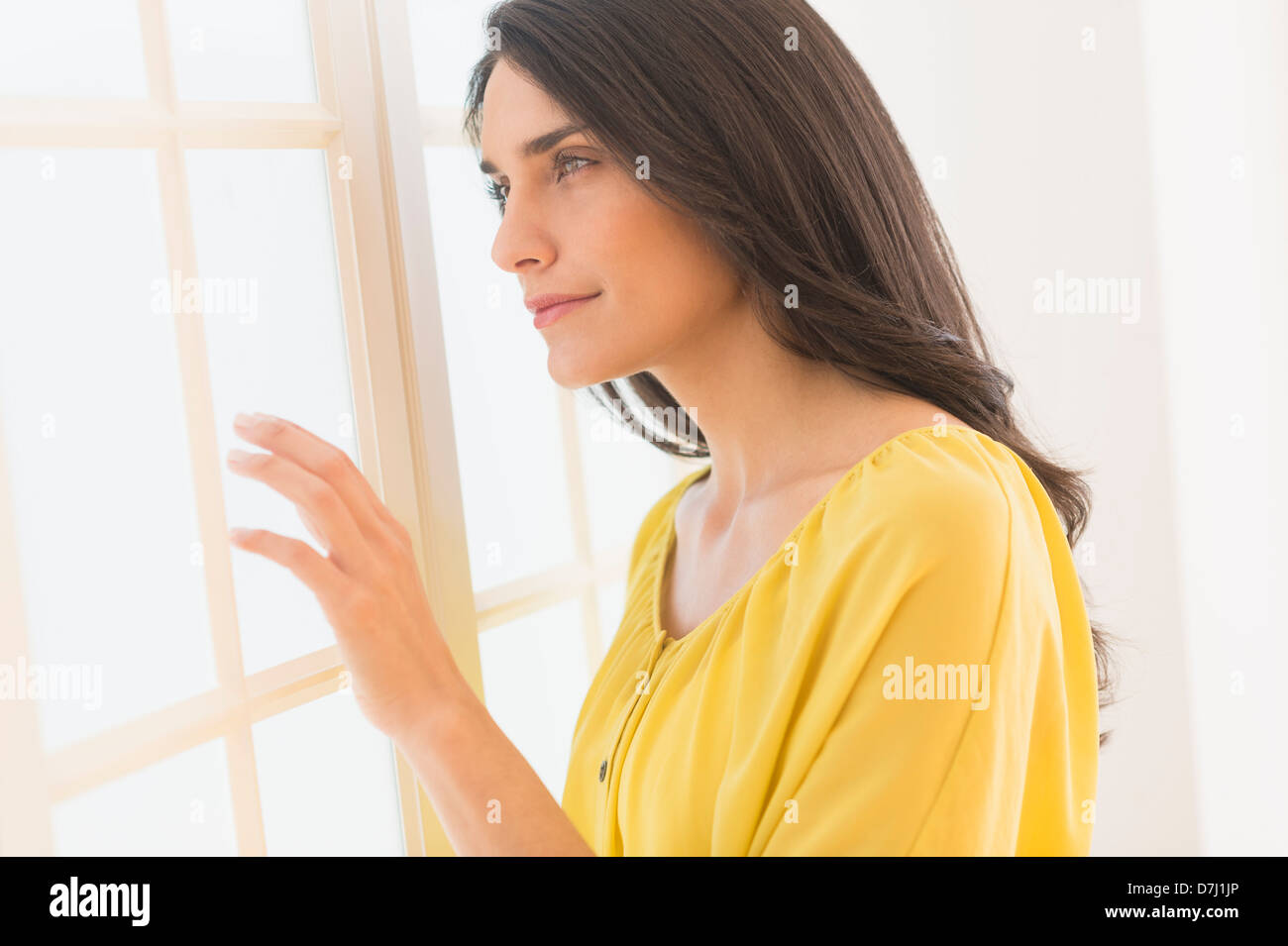 Woman looking through window Stock Photo - Alamy