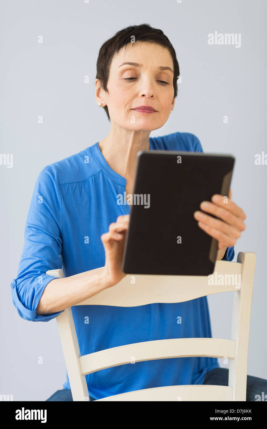 Woman sitting on chair and using digital tablet Stock Photo - Alamy