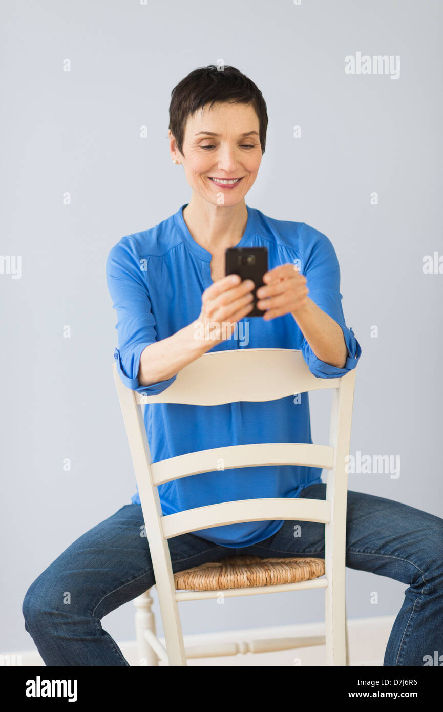 Woman sitting on chair and using mobile phone Stock Photo - Alamy