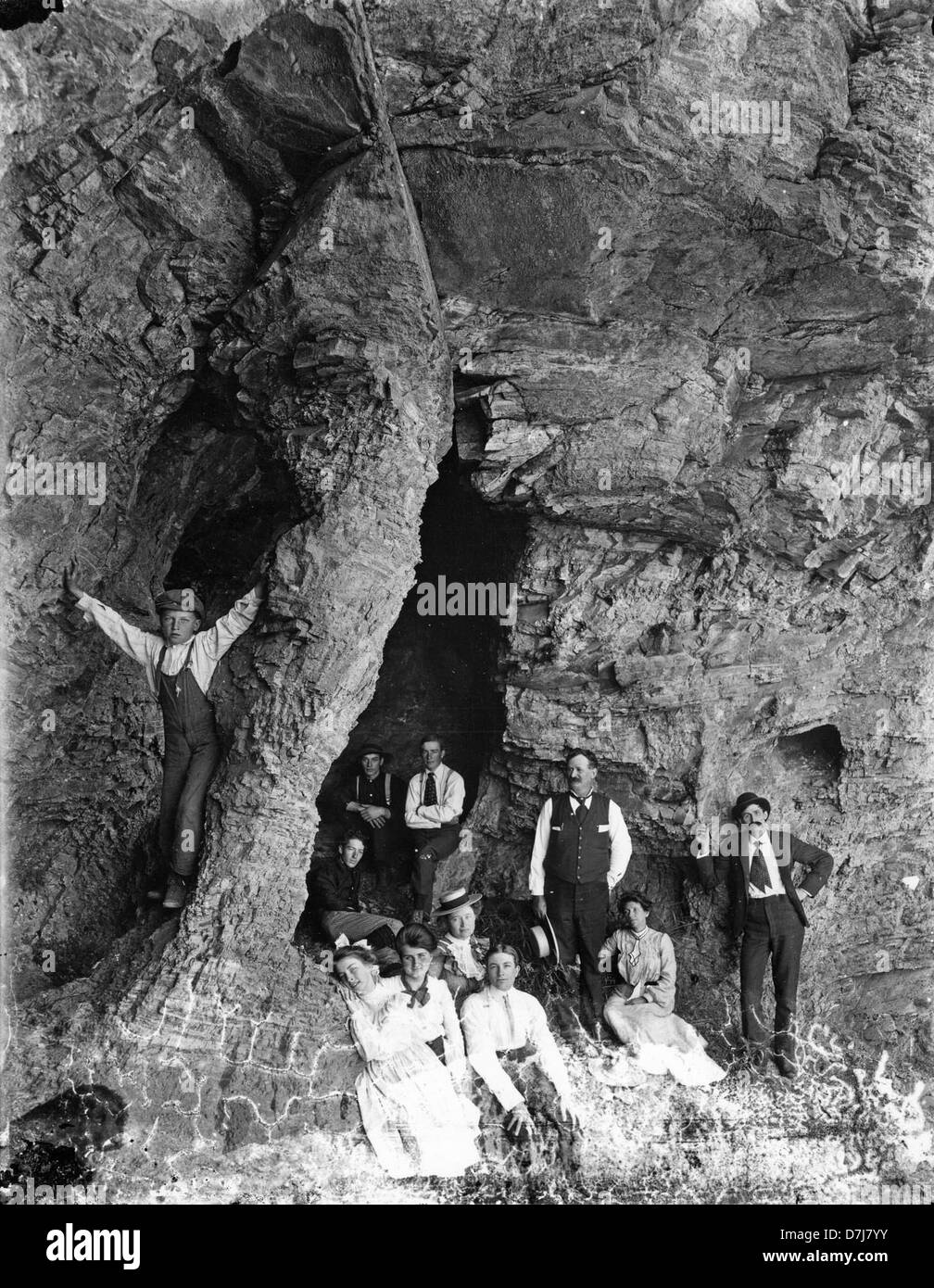 A group of people is gathered at the entrance of a cave, a natural ...