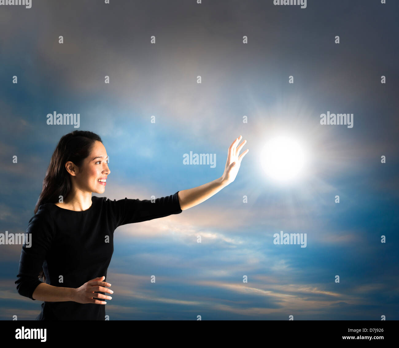 Woman reaching sun on sky, studio shot Stock Photo - Alamy