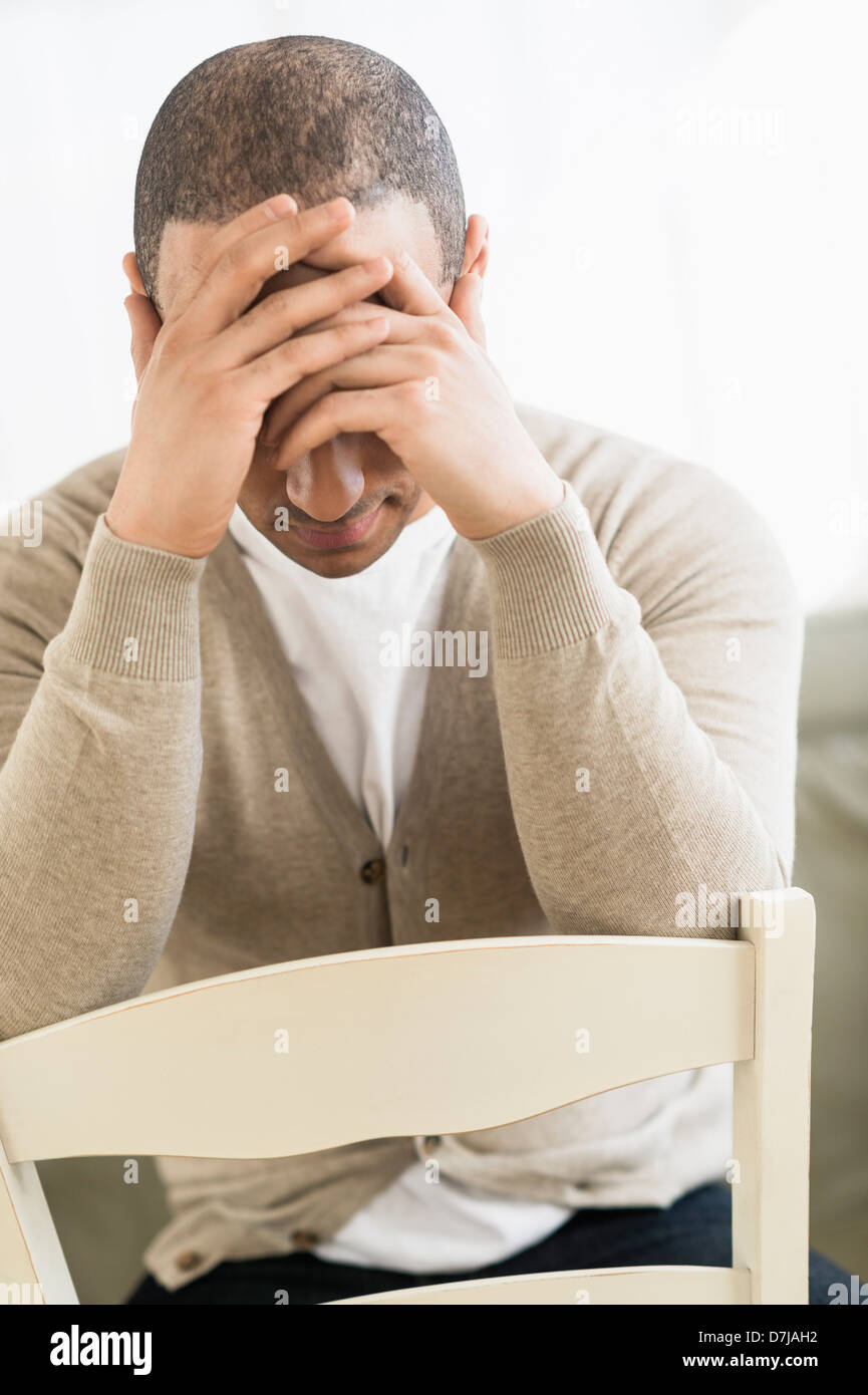 Portrait of young man holding head in hands Stock Photo - Alamy