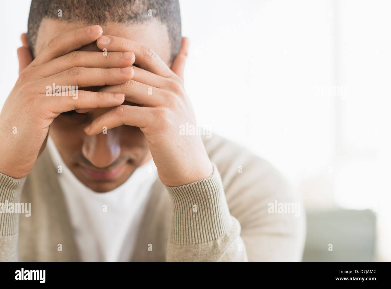 Portrait of young man holding head in hands Stock Photo - Alamy