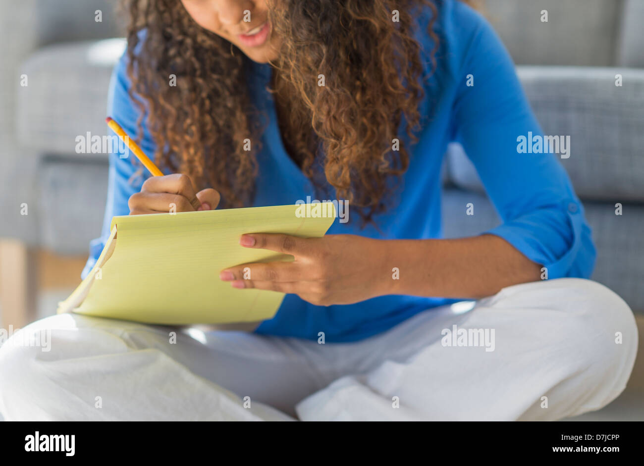 Young woman writing in yellow notepad Stock Photo - Alamy