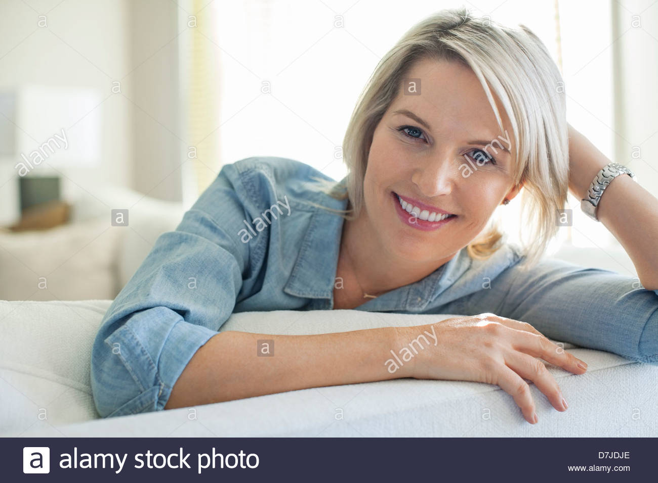 Portrait of smiling woman relaxing on sofa Stock Photo - Alamy