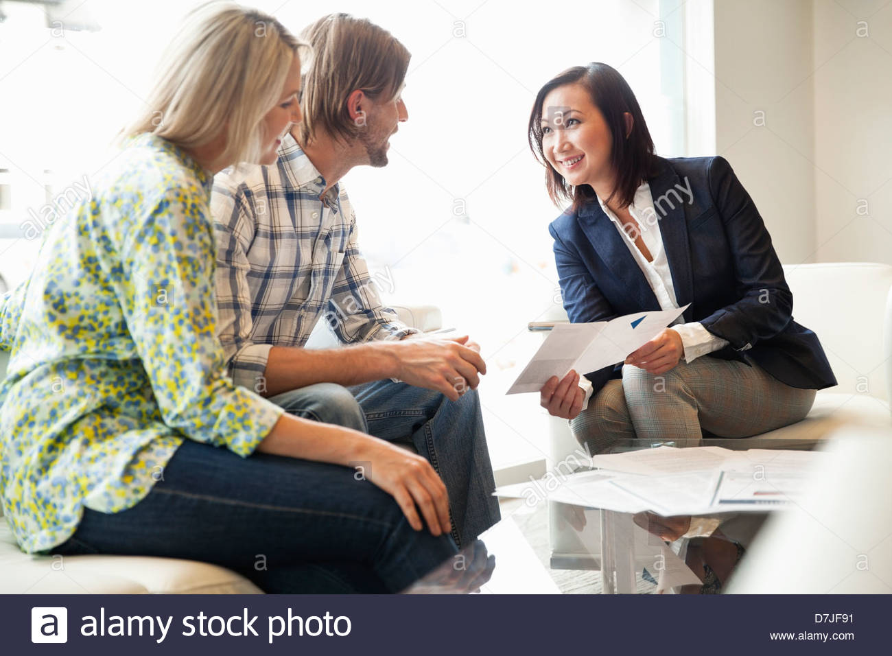 Female financial advisor showing pamphlet to couple at home Stock Photo ...