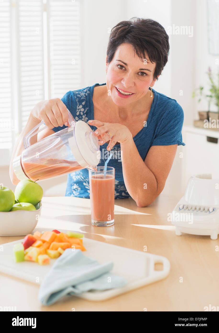Portrait of mature woman pouring glass of smoothie from blender Stock ...