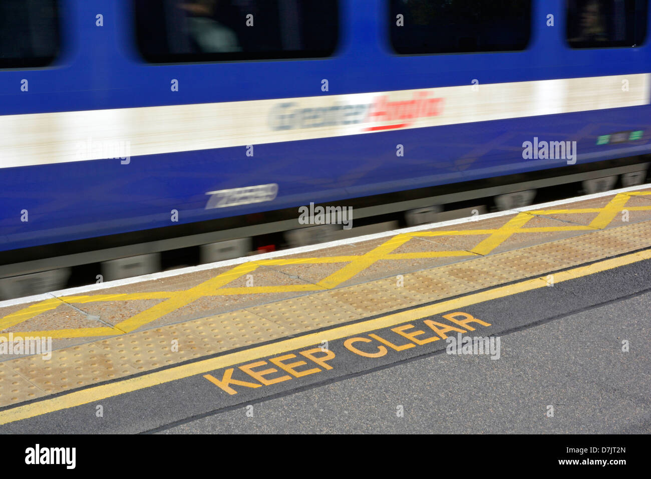 Fast moving train passing station platform edge with keep clear warning ...